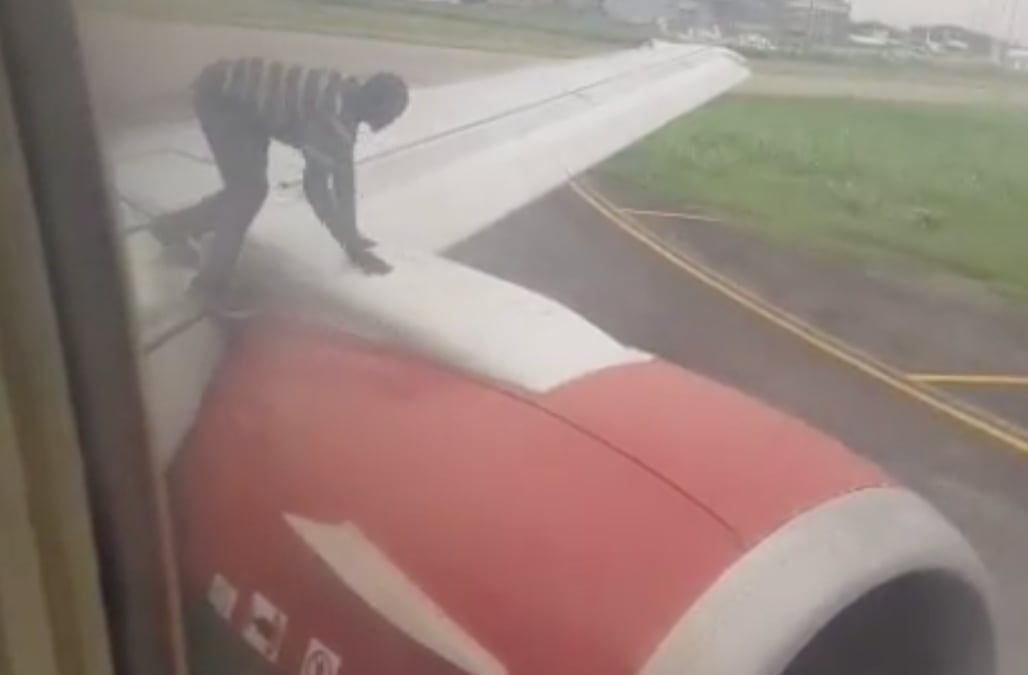 Dramatic video shows man trying to sneak onto plane by climbing onto ...
